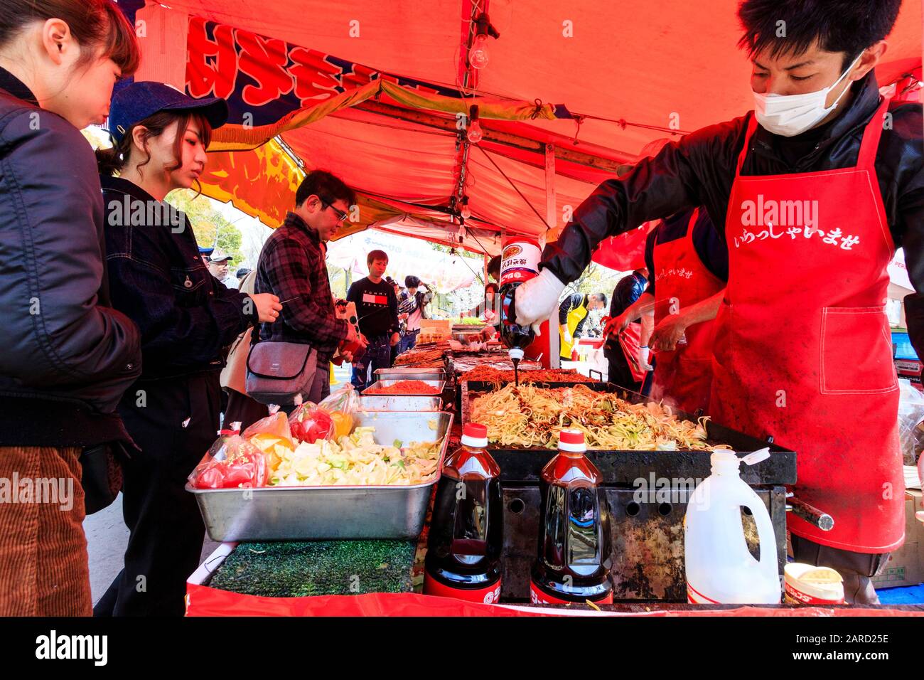 View along of people buying plastic boxes of noodles at food stall with ...