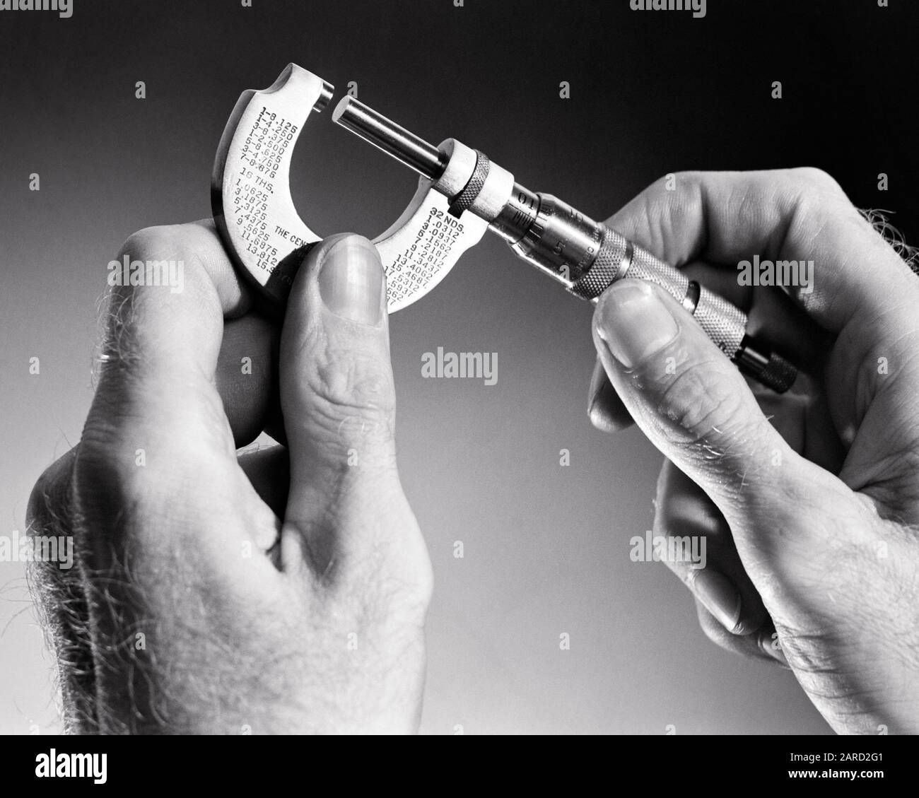 1960s MALE HANDS HOLDING A MICROMETER GAUGE USED TO MEASURE DISTANCE OR ...