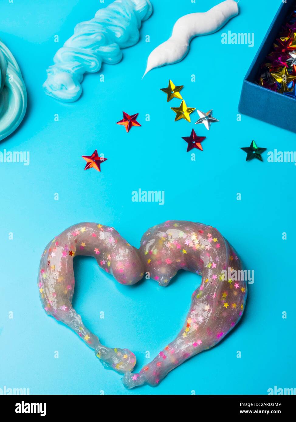 Heart shape glitter slime with colorful stars on a blue table Stock ...