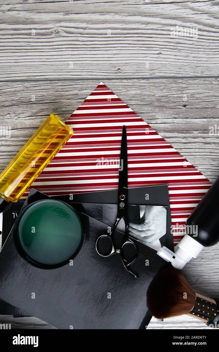 Scissors, shaving gel and hair gel stand on a stack of magazines which ...