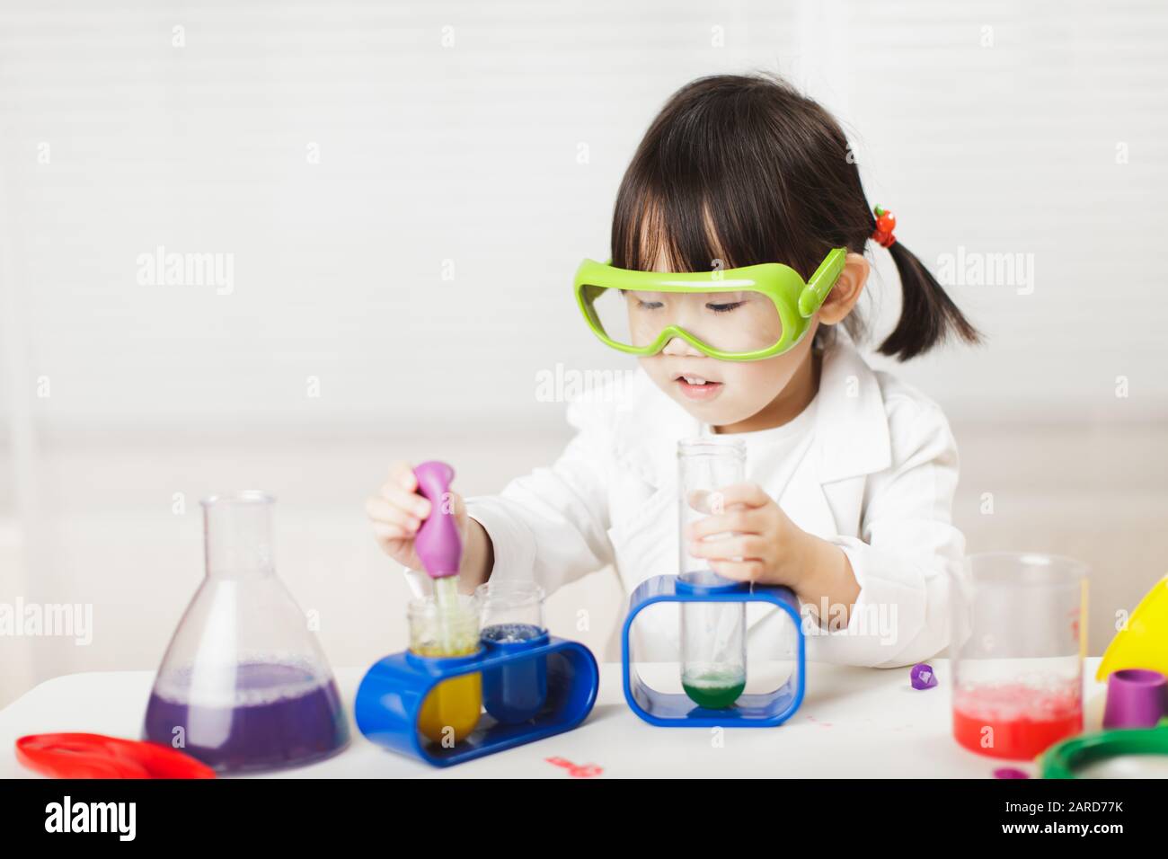 toddler girl pretend play scientist role at home against white ...