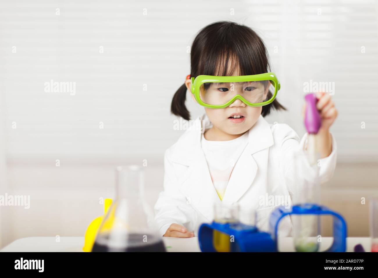 toddler girl pretend play scientist role at home against white ...