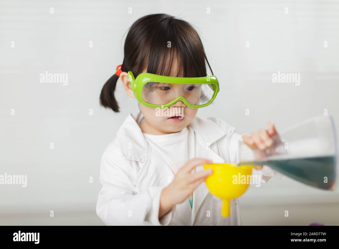 toddler girl pretend play scientist role at home against white ...