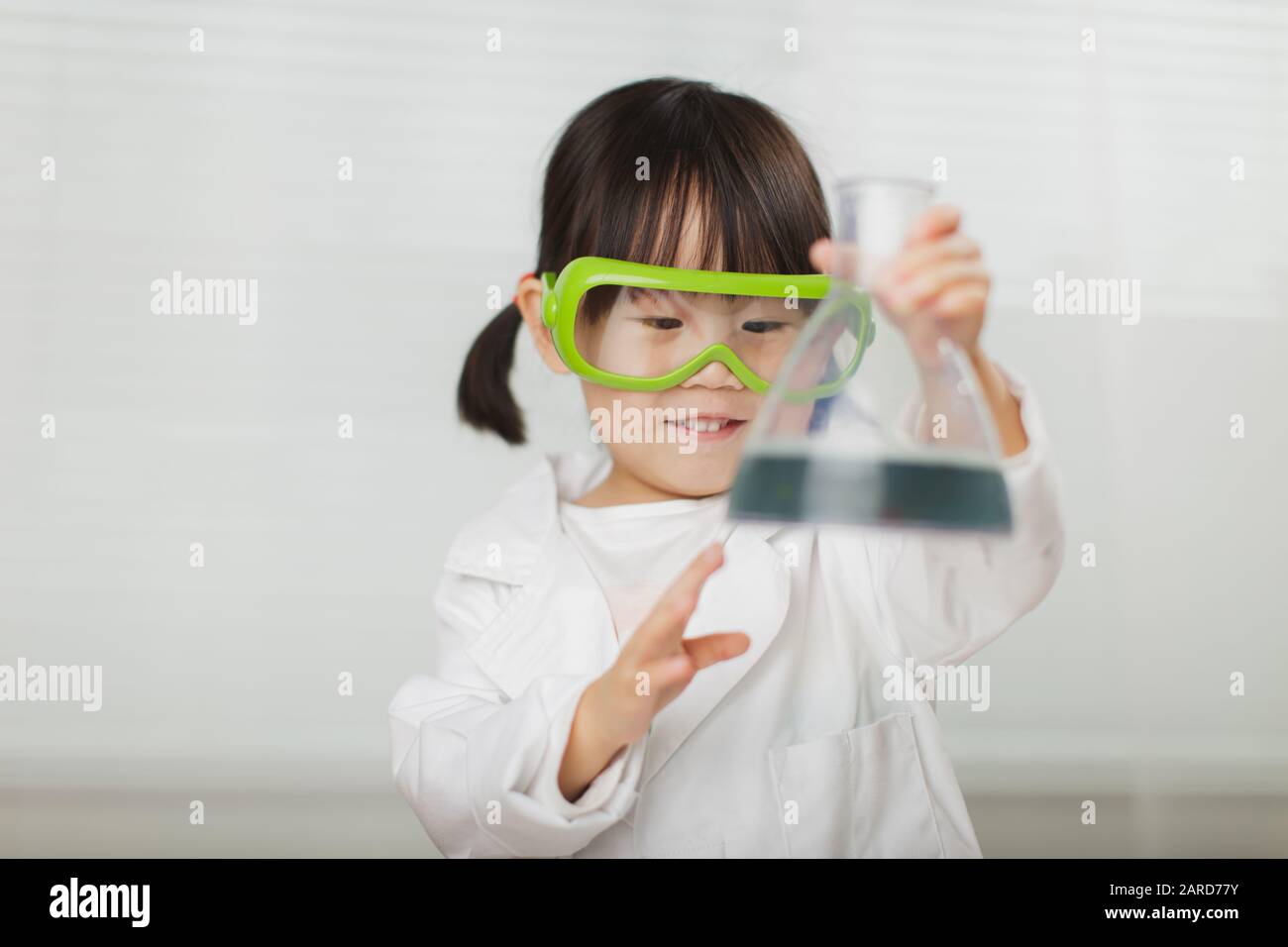 toddler girl pretend play scientist role at home against white ...