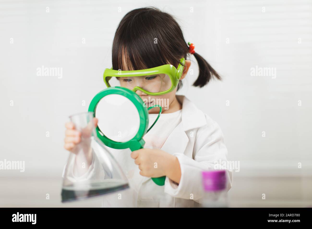 toddler girl pretend play scientist role at home against white ...