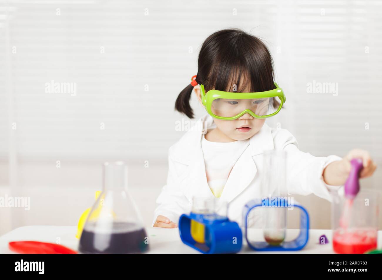 toddler girl pretend play scientist role at home against white ...