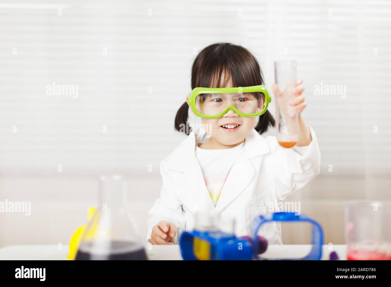 toddler girl pretend play scientist role at home against white ...