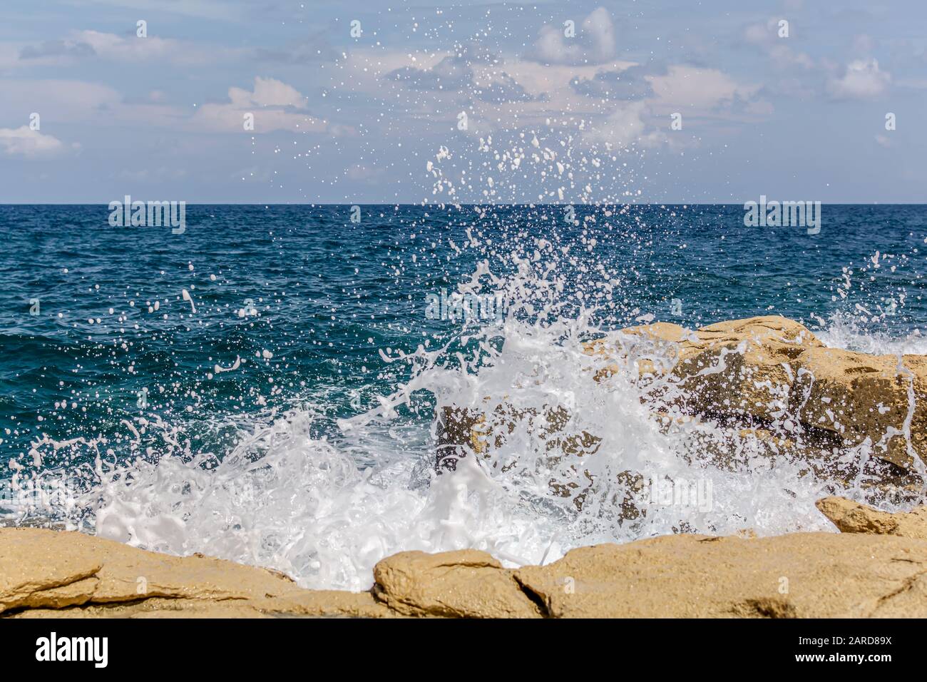 Turquoise wave breaks on rocks Stock Photo - Alamy