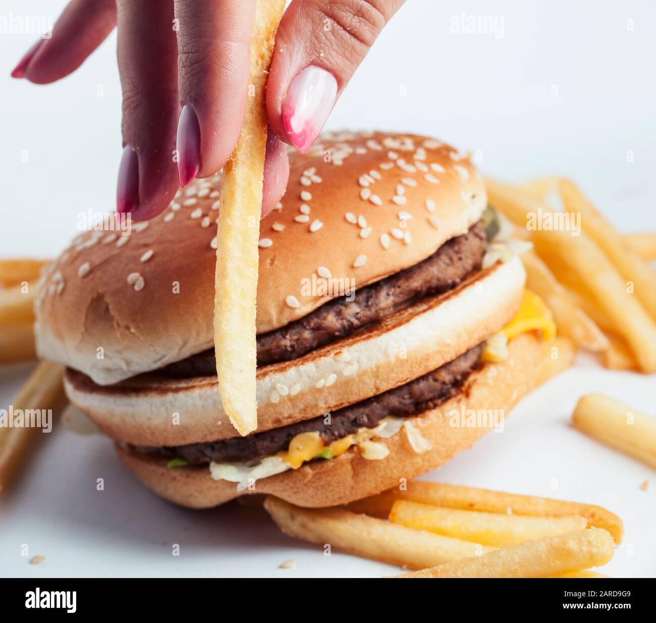 woman hand with manicure holding big burger french fries on background ...