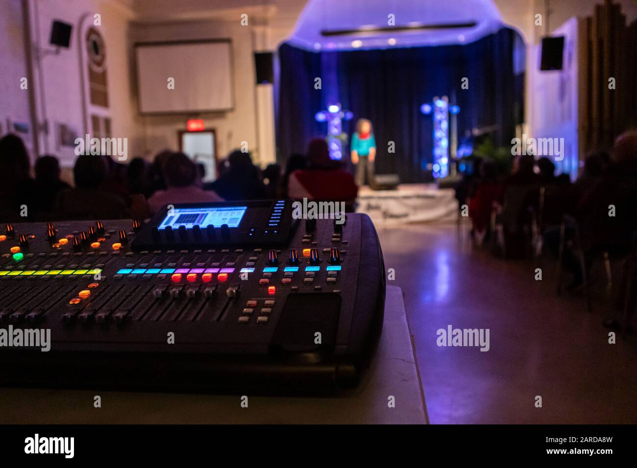 Closeup of sound mixing control machine on table against audience in ...