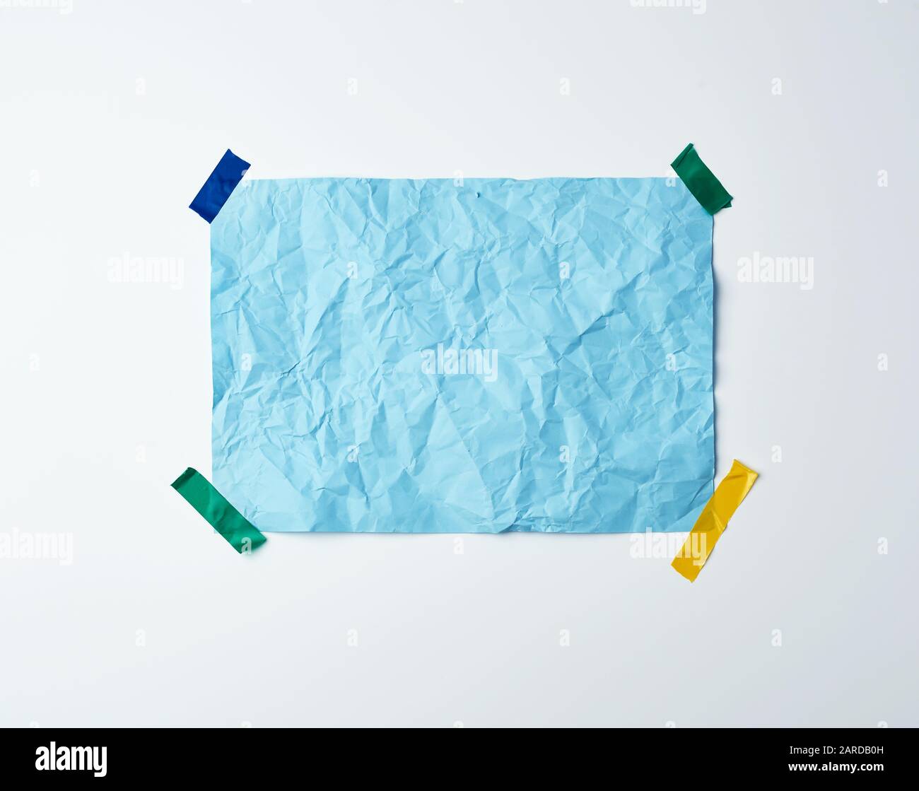 blue crumpled sheet of paper glued with adhesive tape on a white ...