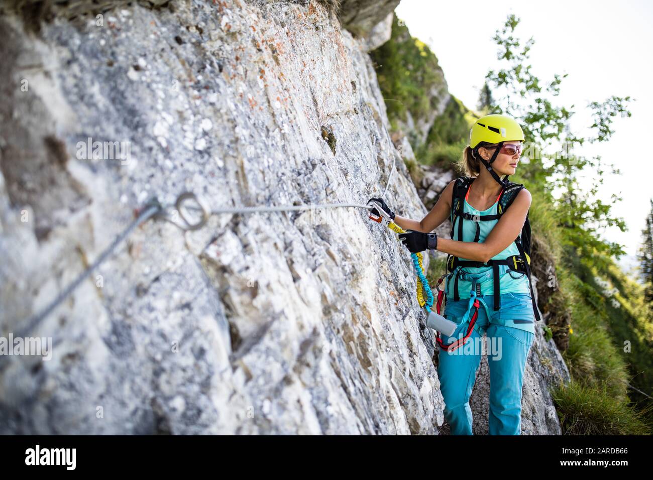 Pretty, female climber on a via ferrata - climbing on a rock in Swiss ...