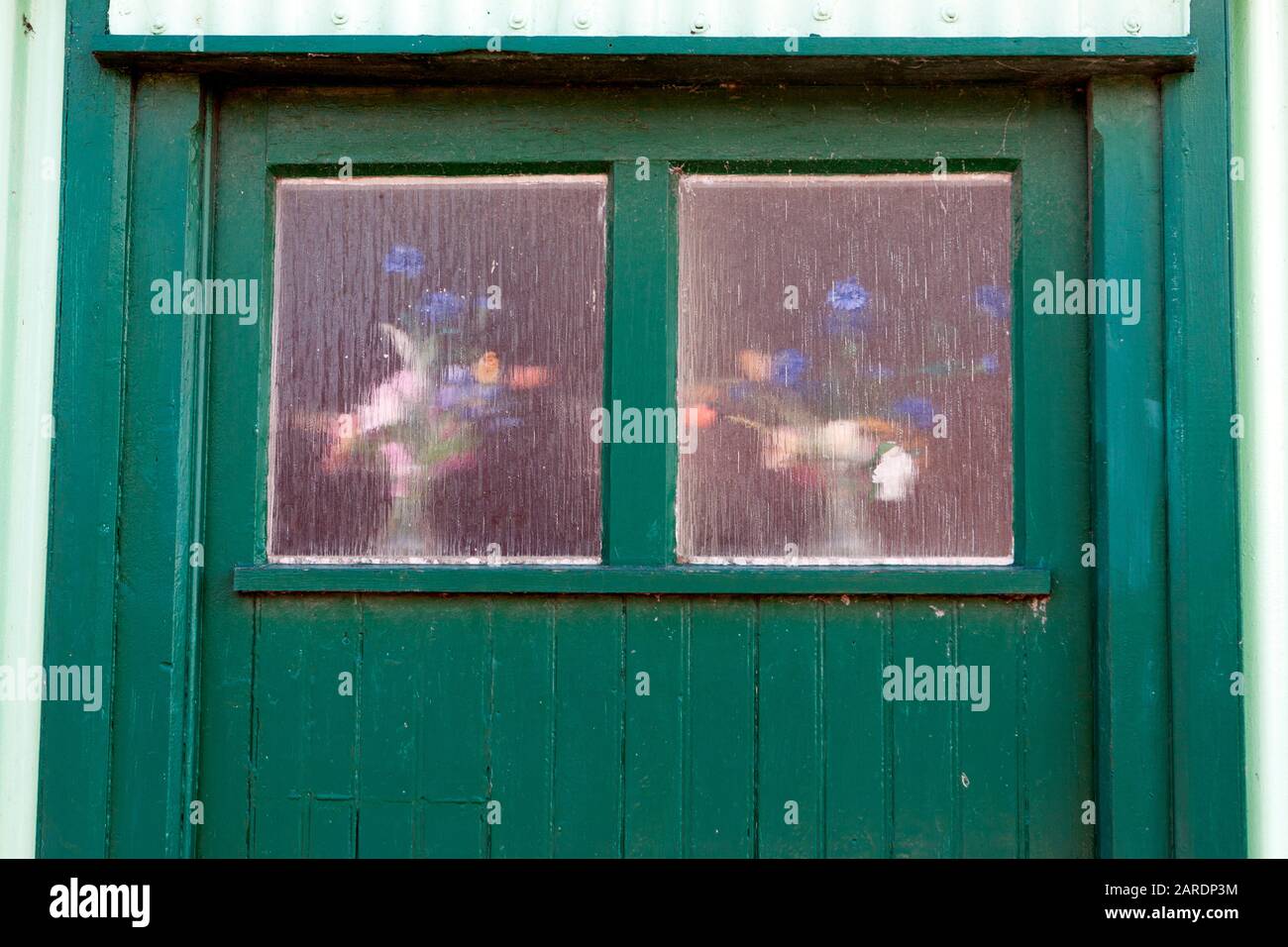 Flowers behind frosted windows of green garage doors Stock Photo - Alamy