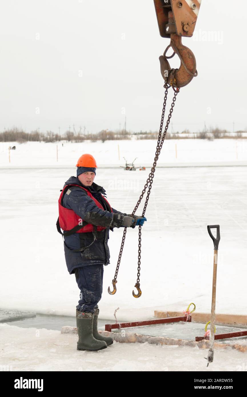Slinger works with a truck crane on ice Stock Photo - Alamy