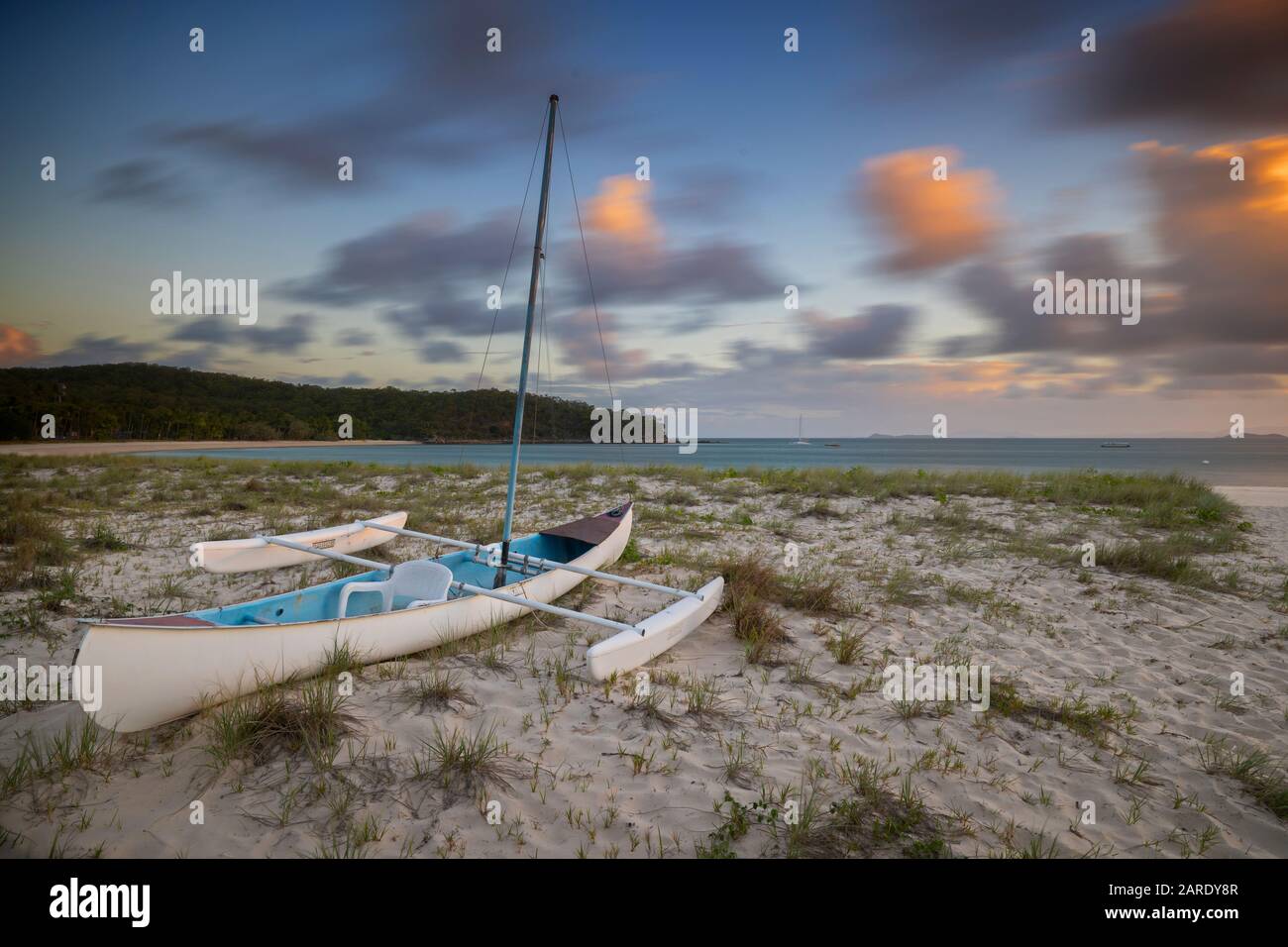 canoe with mast and outriggers in sand dunes on beach at sunset Stock ...