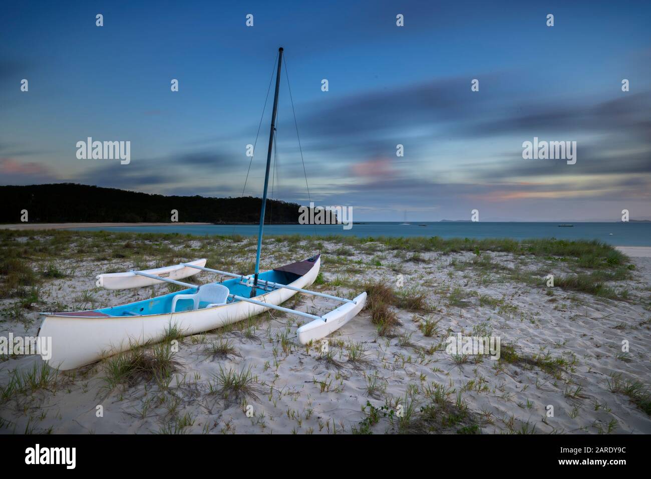 canoe with mast and outriggers in sand dunes on beach at sunset Stock ...
