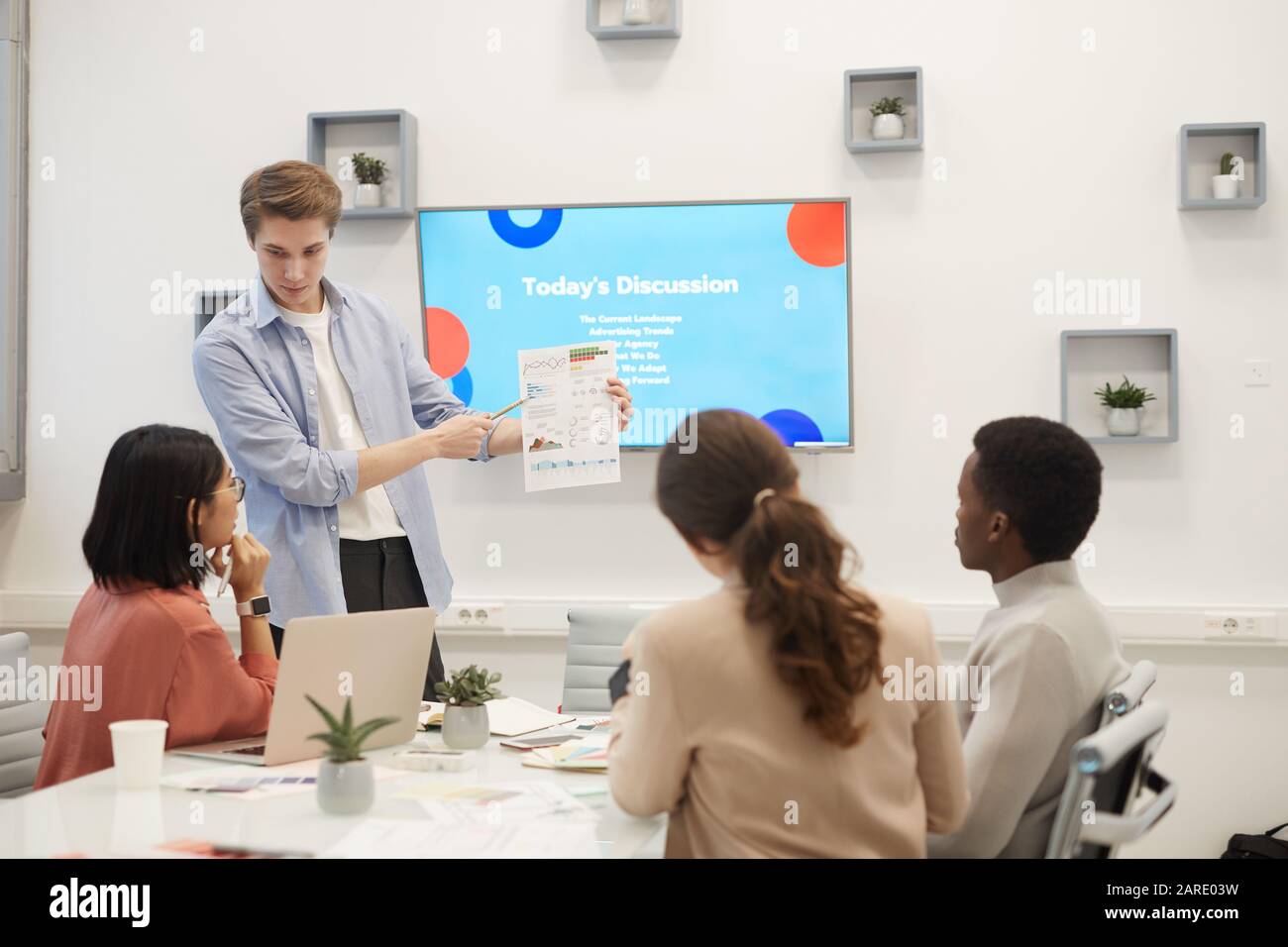 Portrait of young man showing data graphs while giving presentation ...