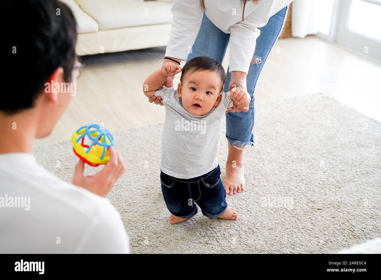 Asian baby boy toddler taking first steps. Family of father and mother ...