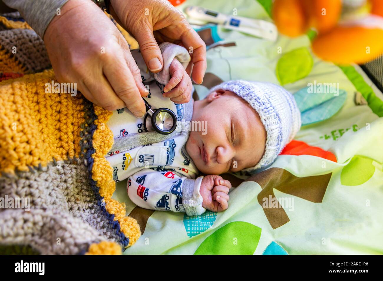 A beautiful baby boy is seen in the first days of life, wrapped in soft ...
