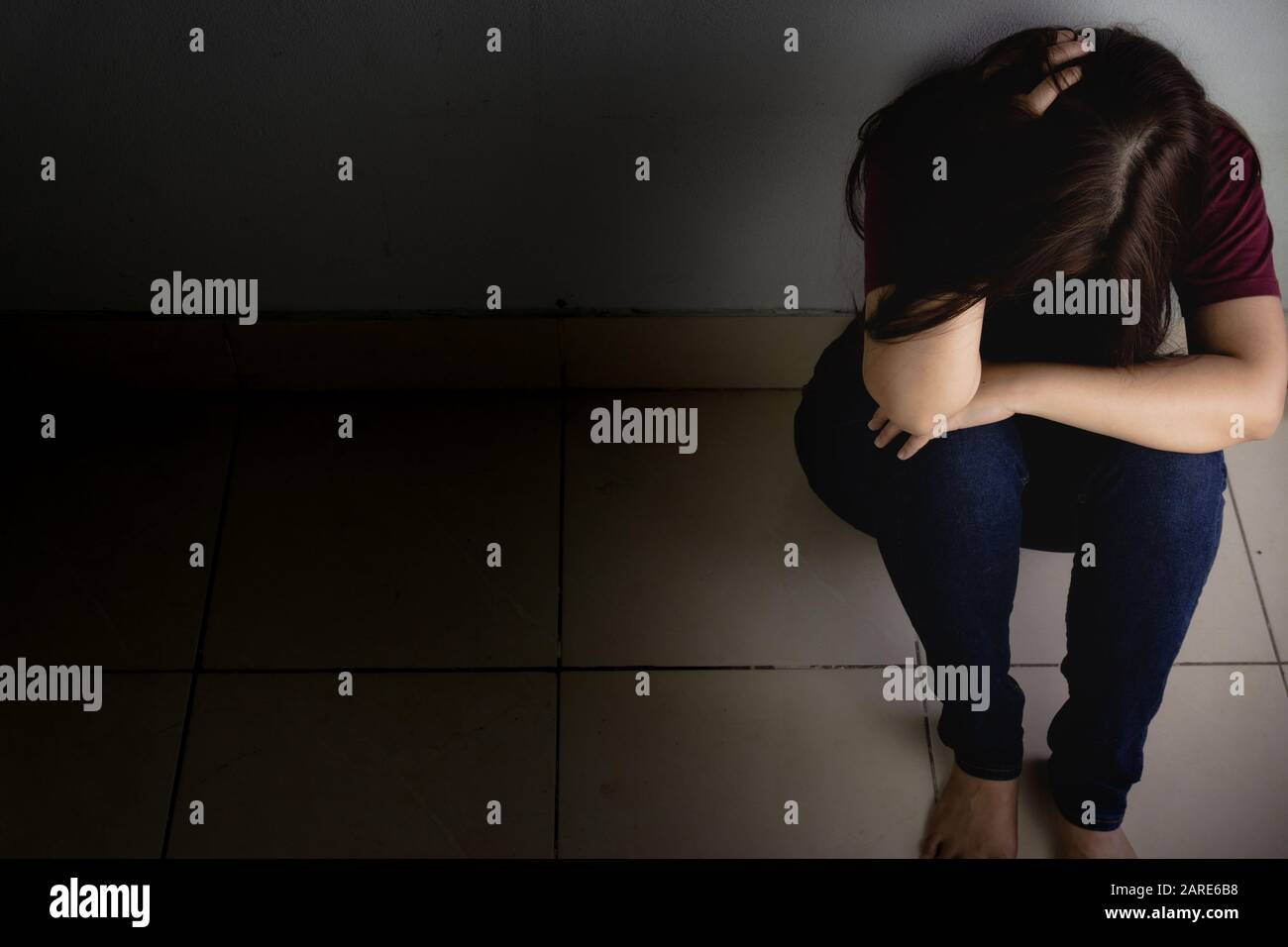 sad woman hug her knee and cry sitting alone in a dark room. Depression ...