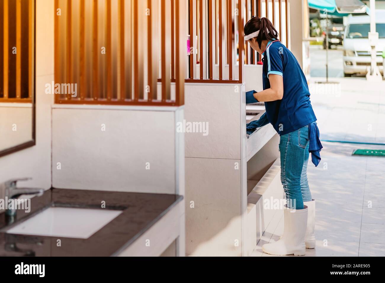 Female janitor using fabric and a detergent cleaning sink and tap in ...