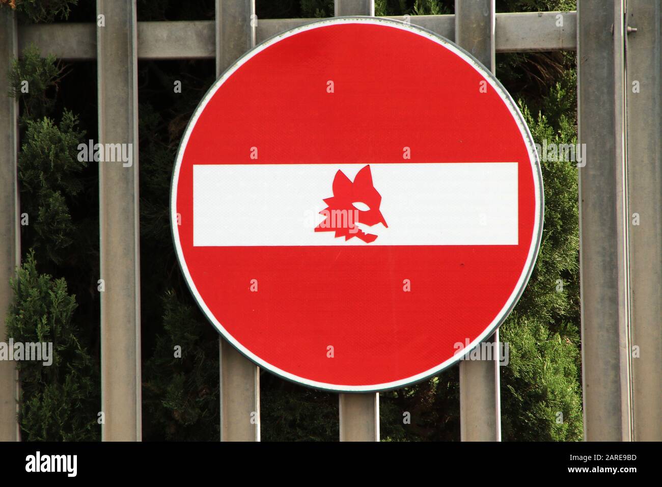 Red traffic sign with a face on it surrounded by evergreens under the ...