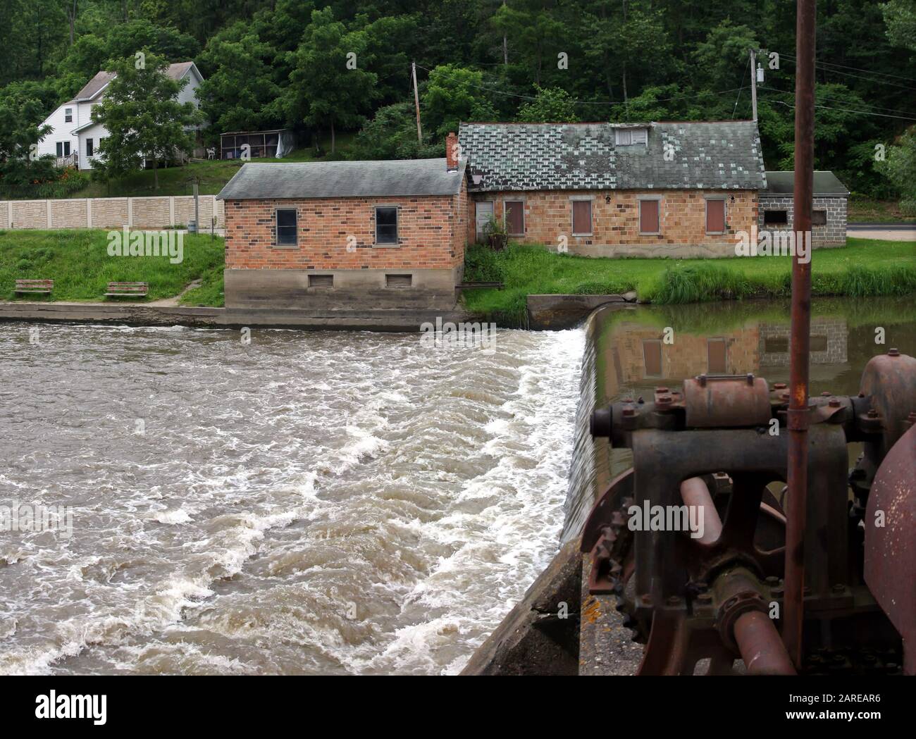 Rapid flow of river dam with a brick house building on the grass area ...