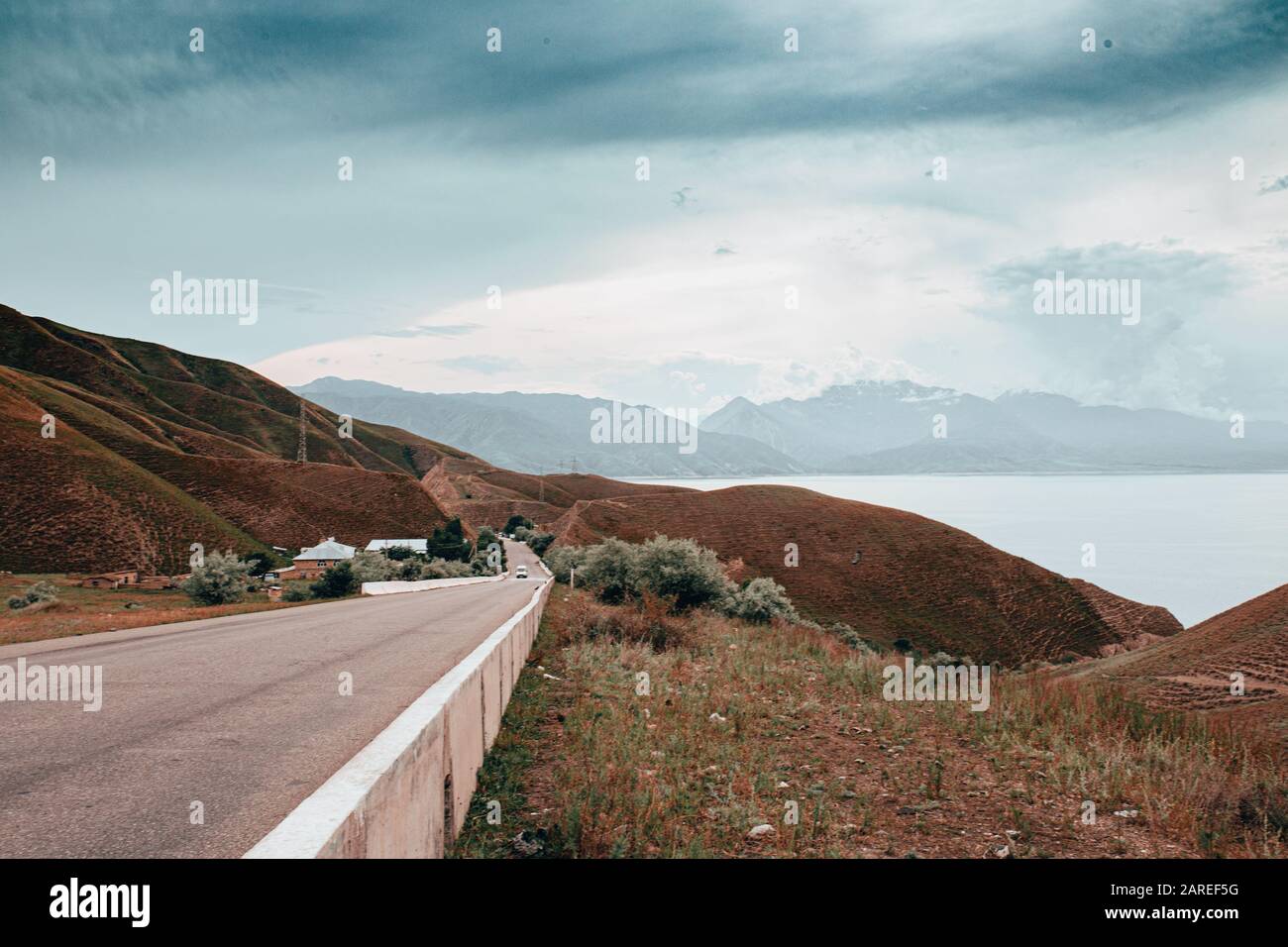 Landscape with mountains, clouds, water, and roads in a Central Asian ...