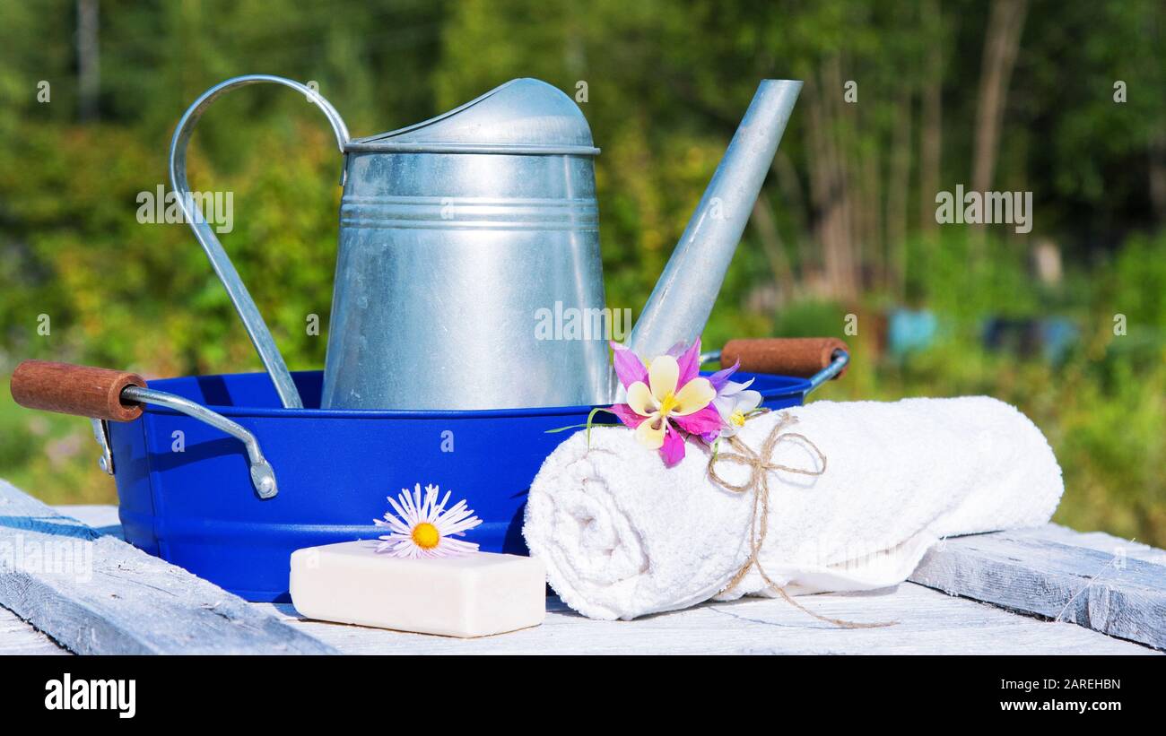 Metal watering can, purple basin, toilet soap and white towel with ...