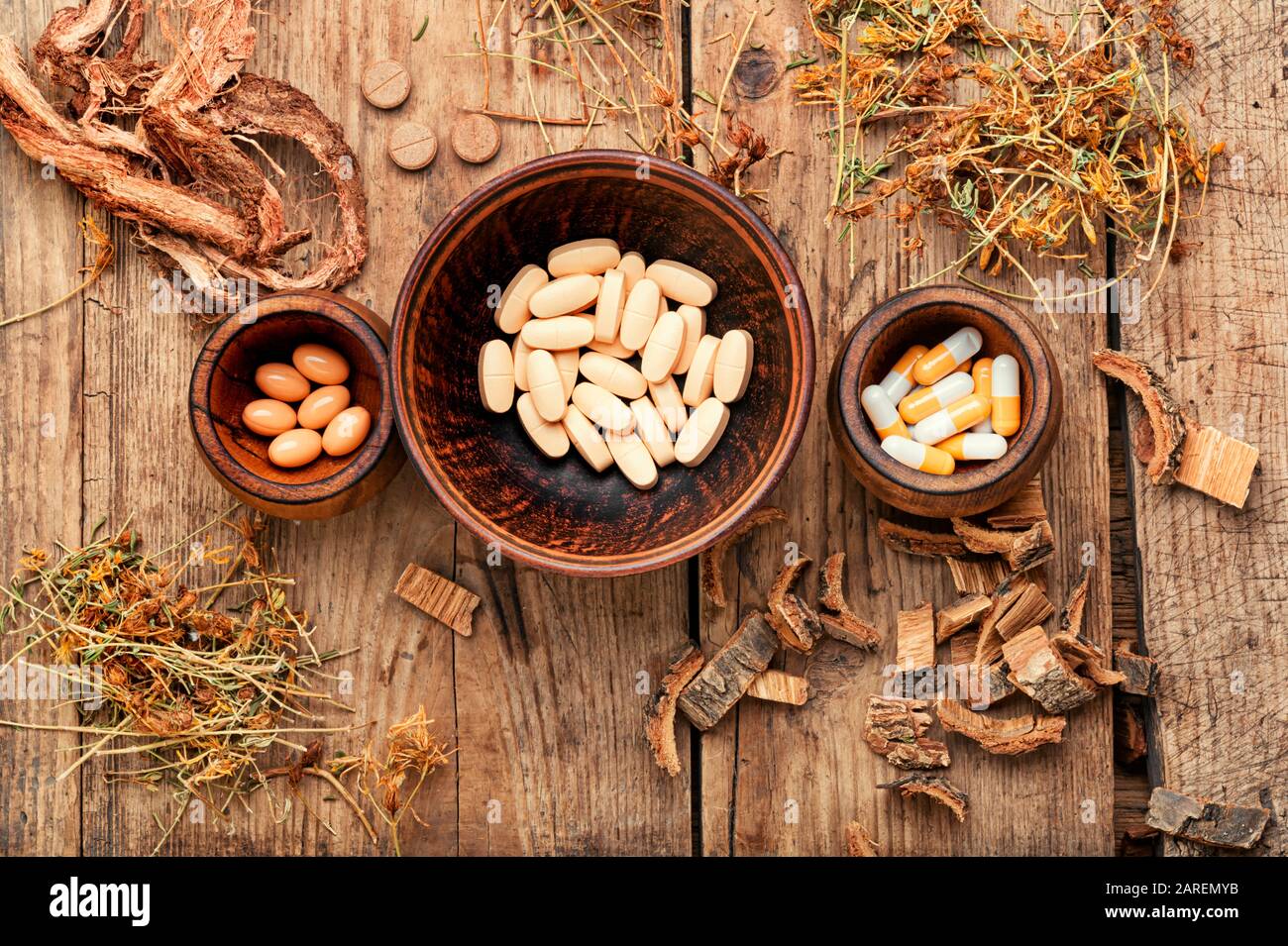 Herbal medical tablets with healing plant on wooden table.Alternative ...
