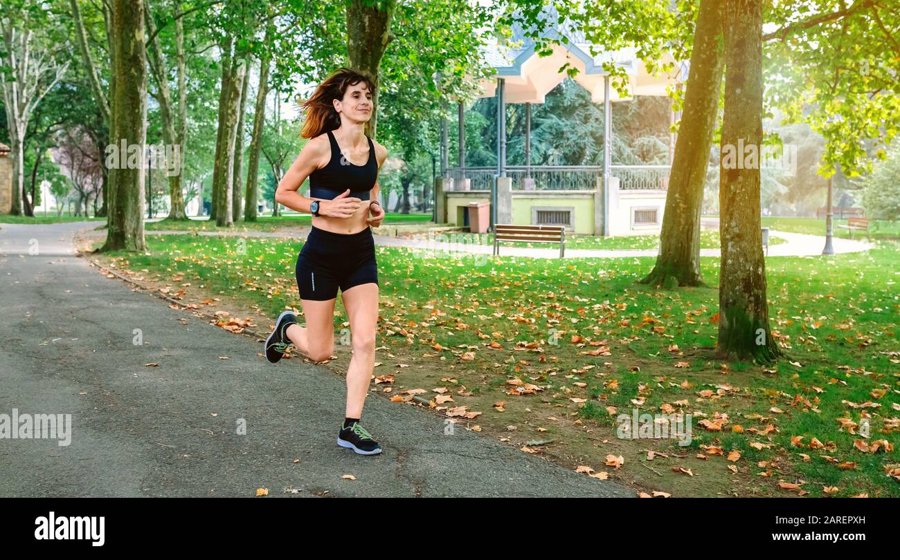 Female athlete running through a park Stock Photo - Alamy
