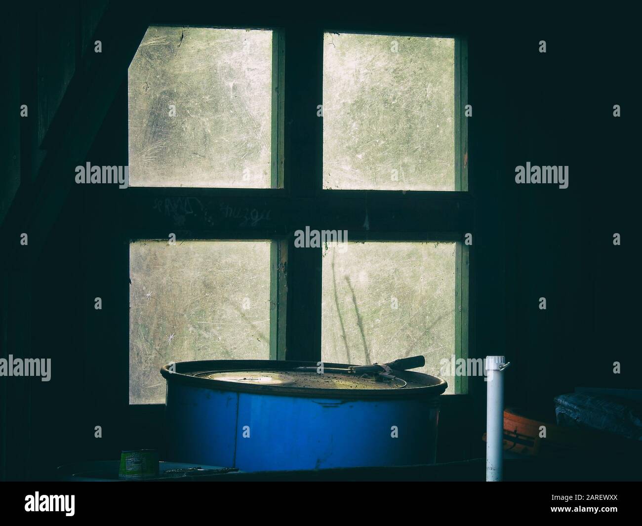 Junk room with an old dirty window and a blue barrel Stock Photo - Alamy