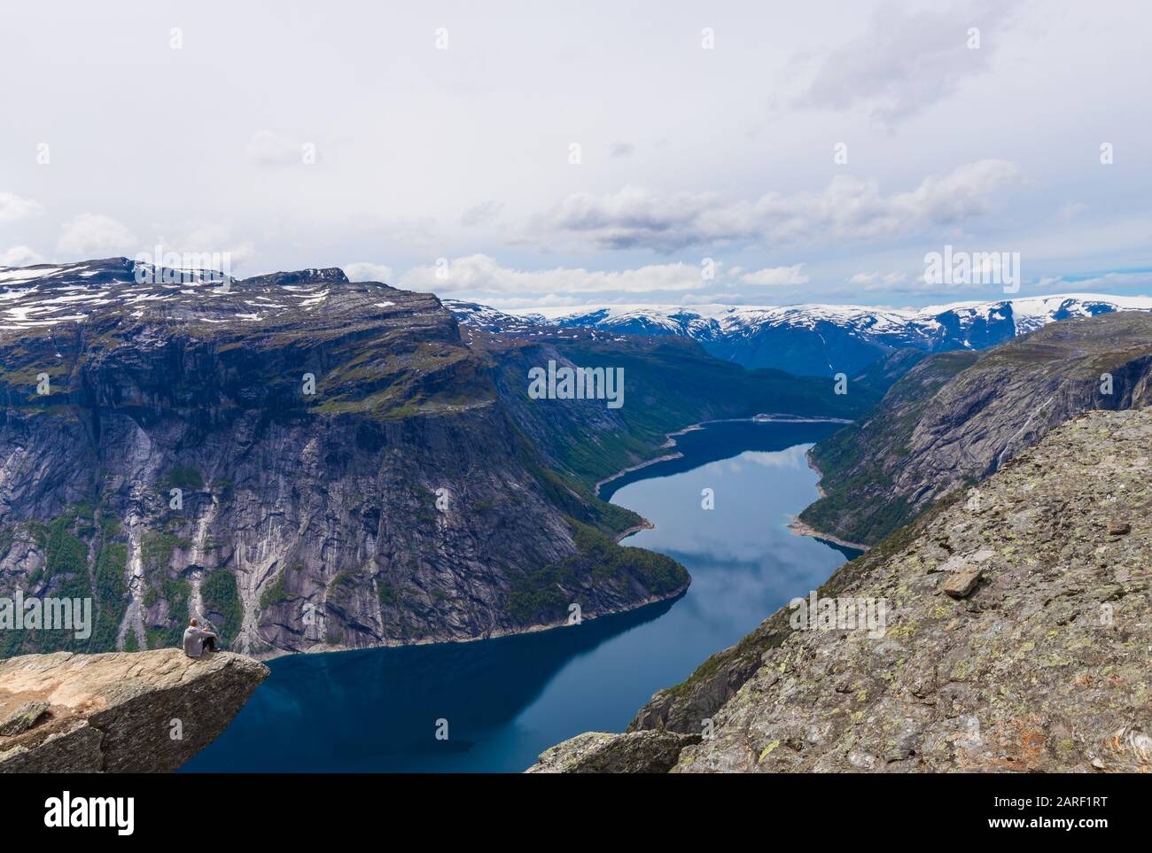 Man Sitting On Edge Of Cliff At Trolltunga Mountain In Norway Stock ...