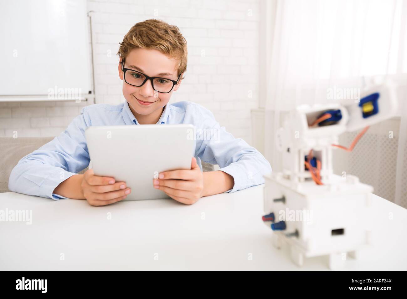 Smart boy programming robot with tablet at stem educational lesson ...