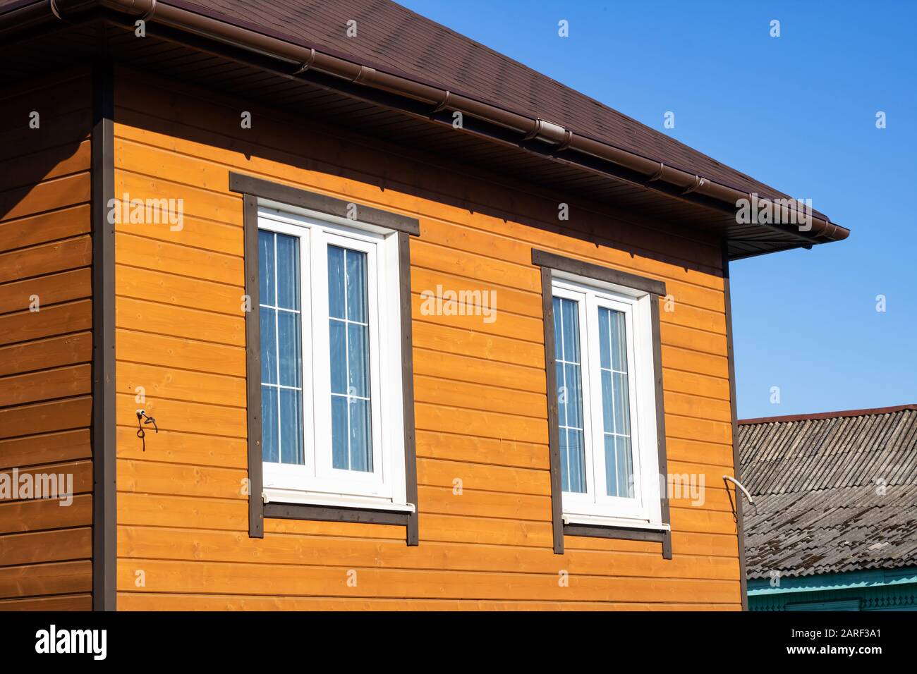 Exterior view of a new wooden house and two windows Stock Photo - Alamy