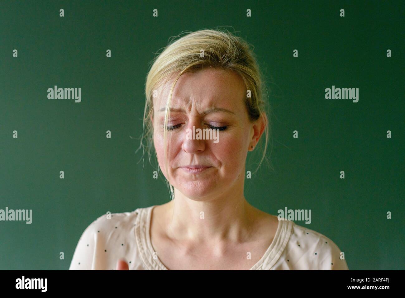 Thoughtful school teacher frowning in concentration with closed eyes in ...