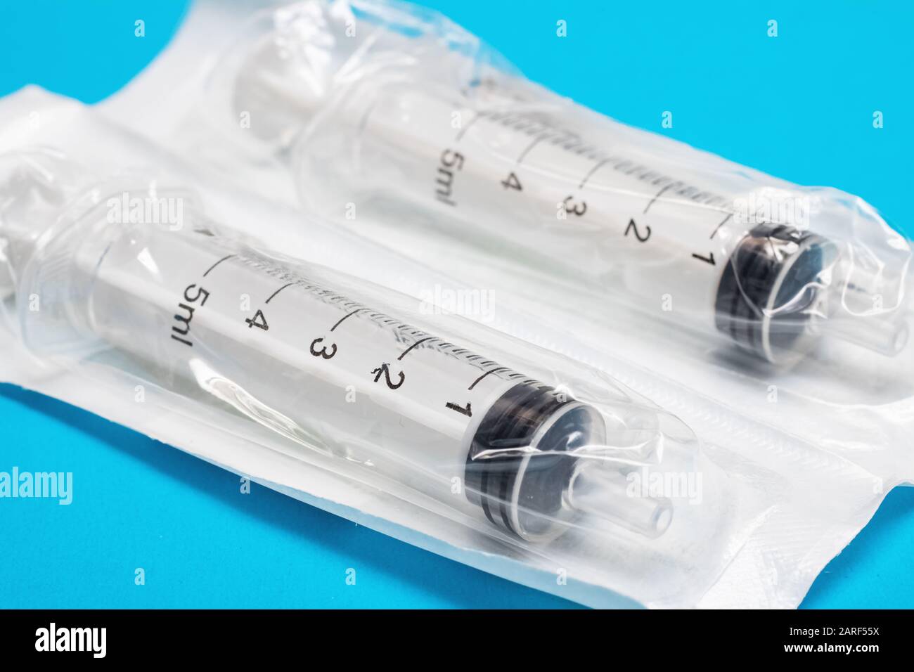 Disposable syringes in packaging on blue background Stock Photo - Alamy