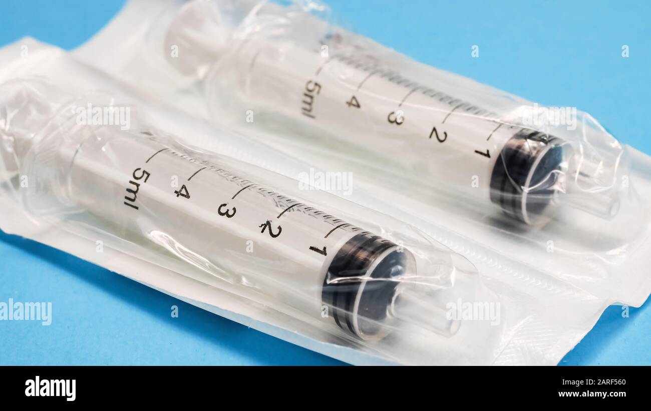 Disposable syringes in packaging on blue background Stock Photo - Alamy