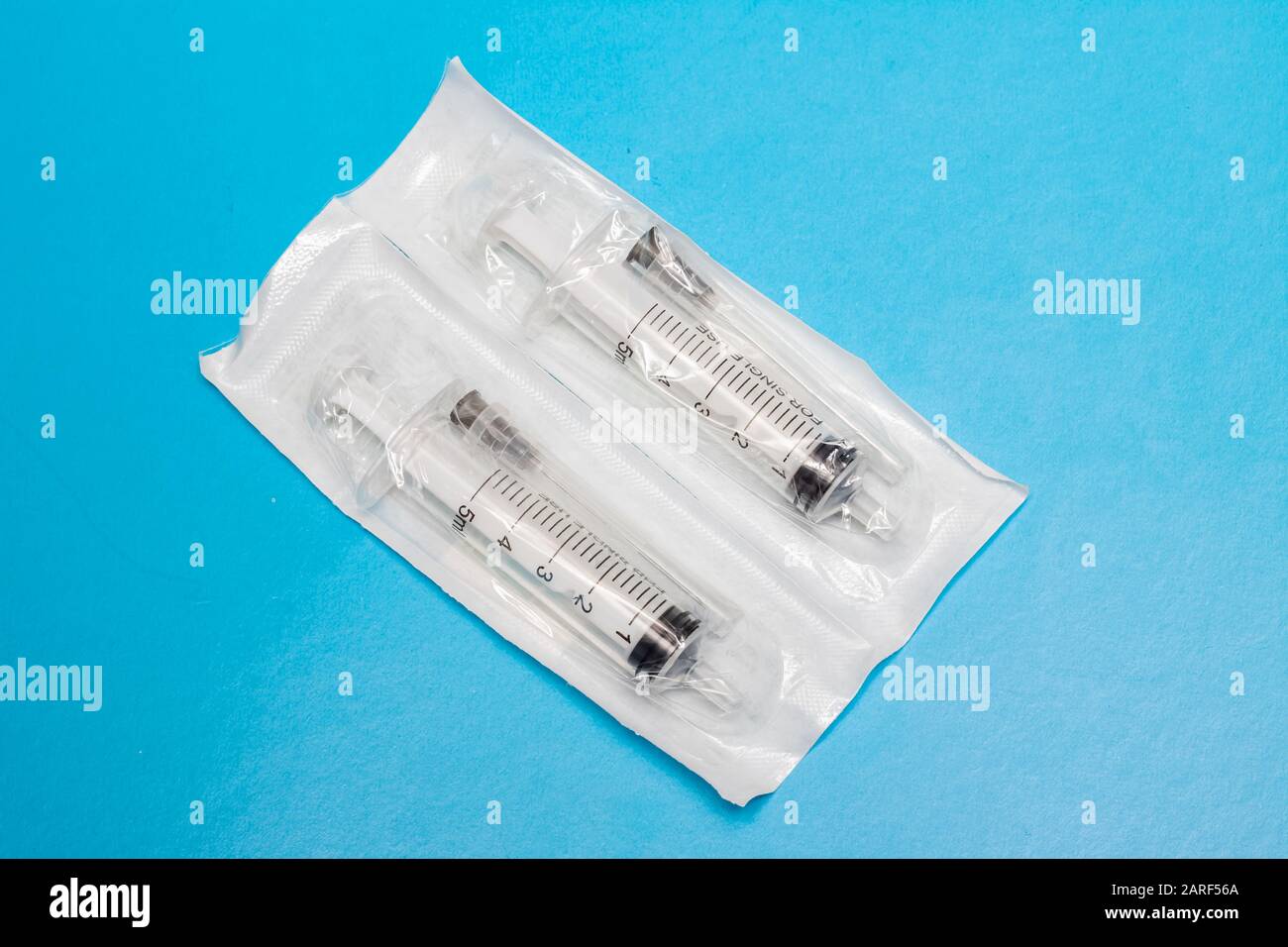 Disposable syringes in packaging on blue background Stock Photo - Alamy