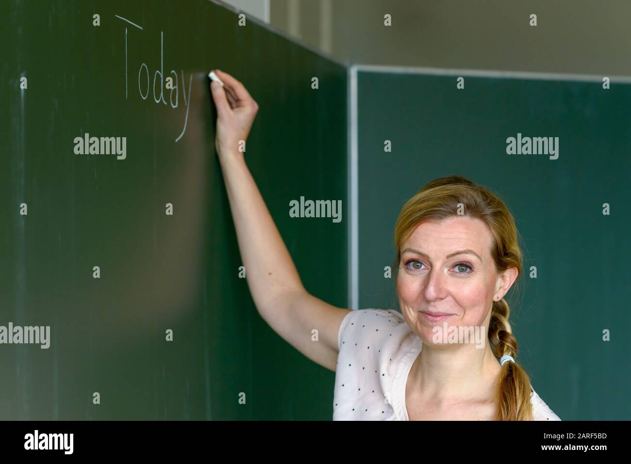 Close Up Portrait Of Female Teacher In Class Writing On The Chalkboard