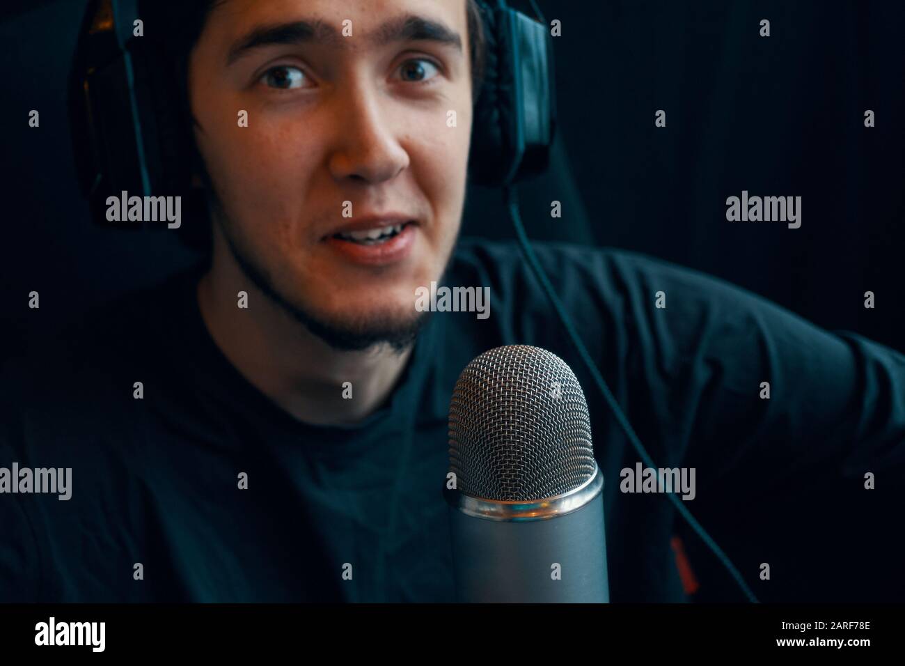 Podcast studio. Man is broadcasting on the air on a speaker. Looking at ...