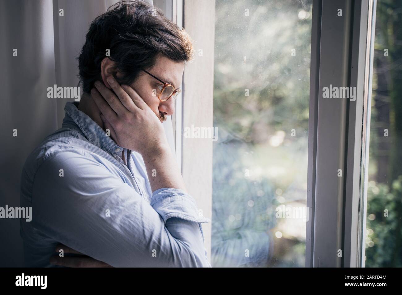 Portrait of one guy longing and looking through window Stock Photo - Alamy