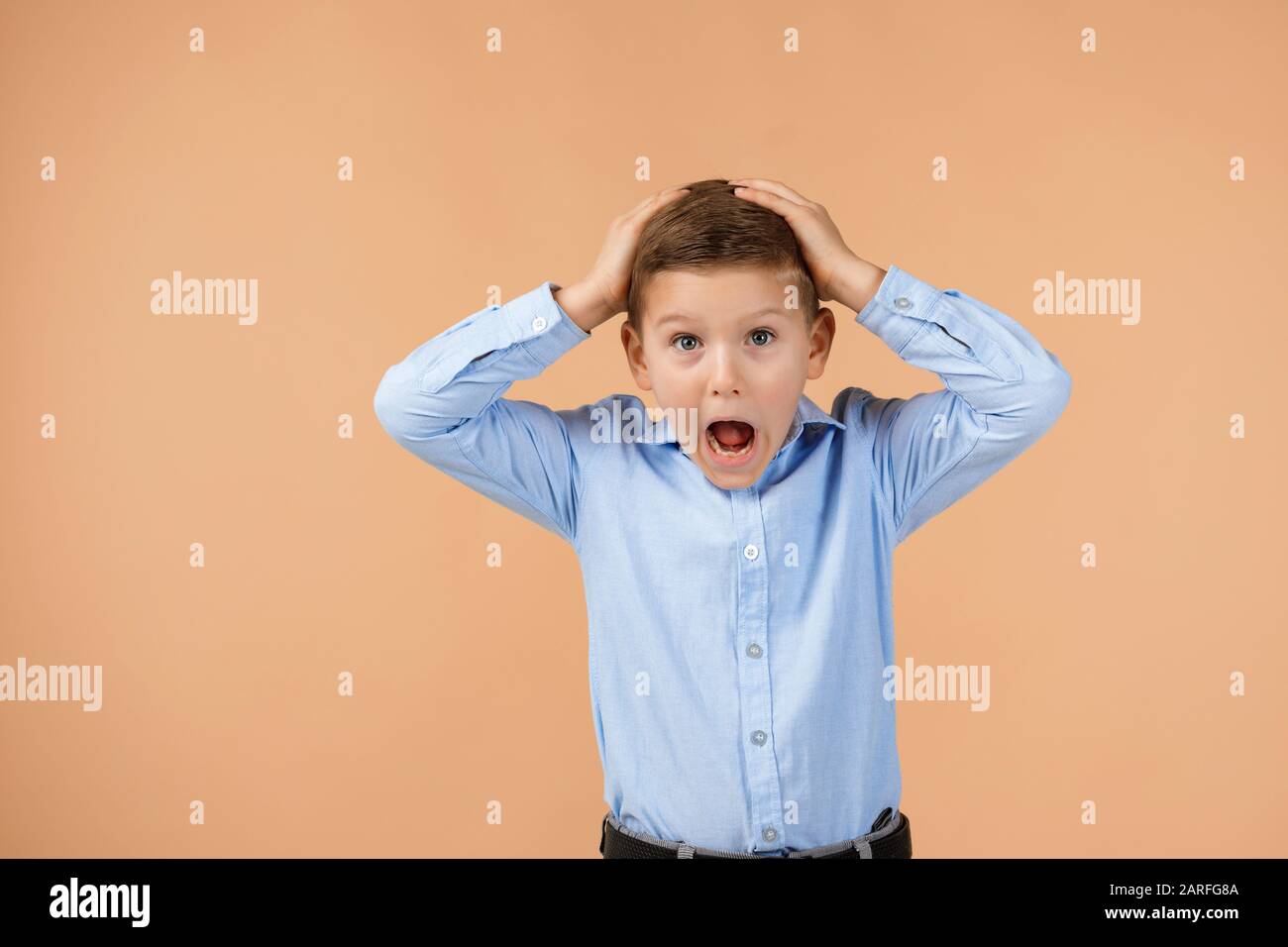 happy surprised little child boy looking to camera on beige background ...