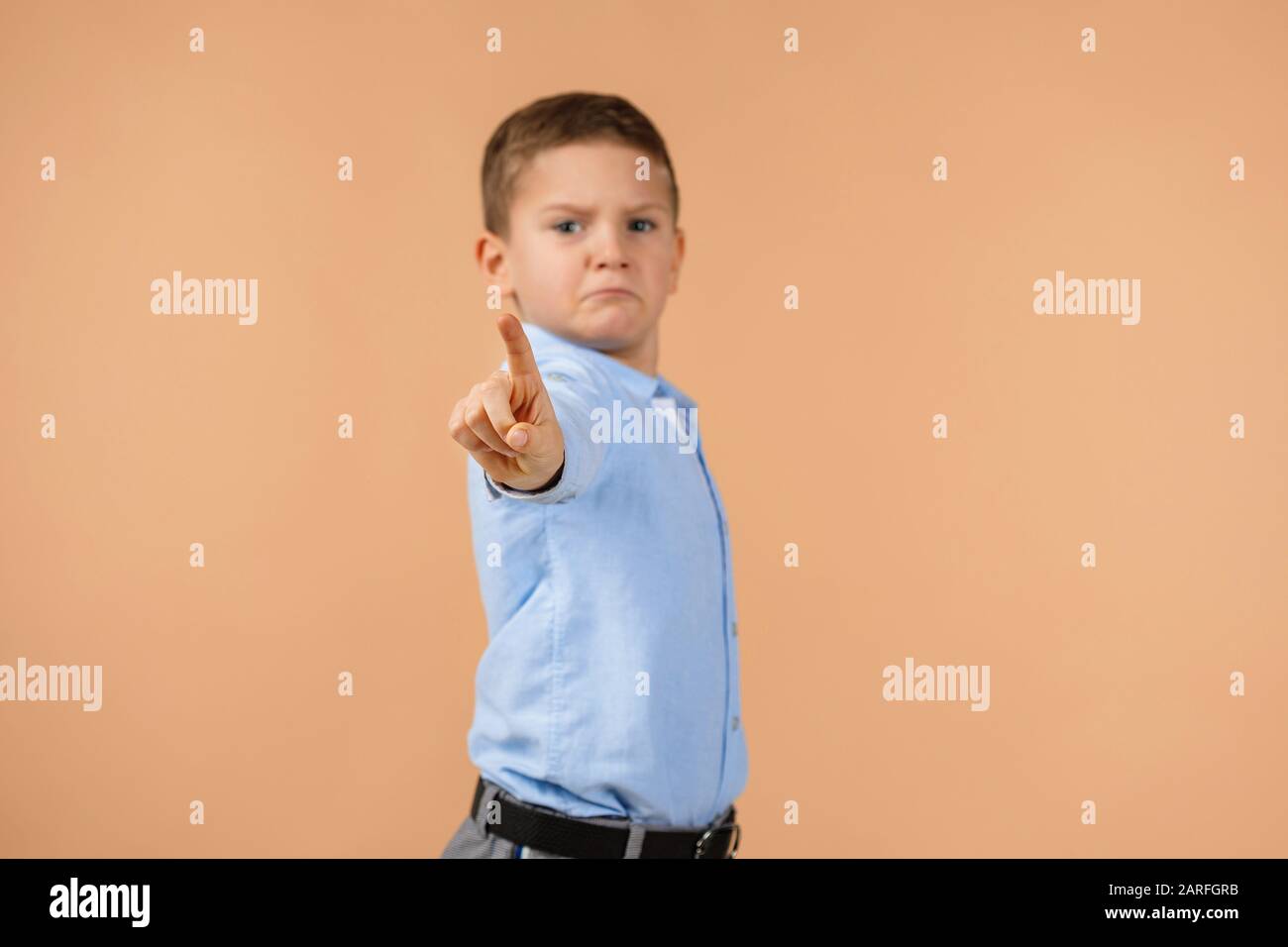 Cute little boy in shirt pointing camera on beige background. child ...