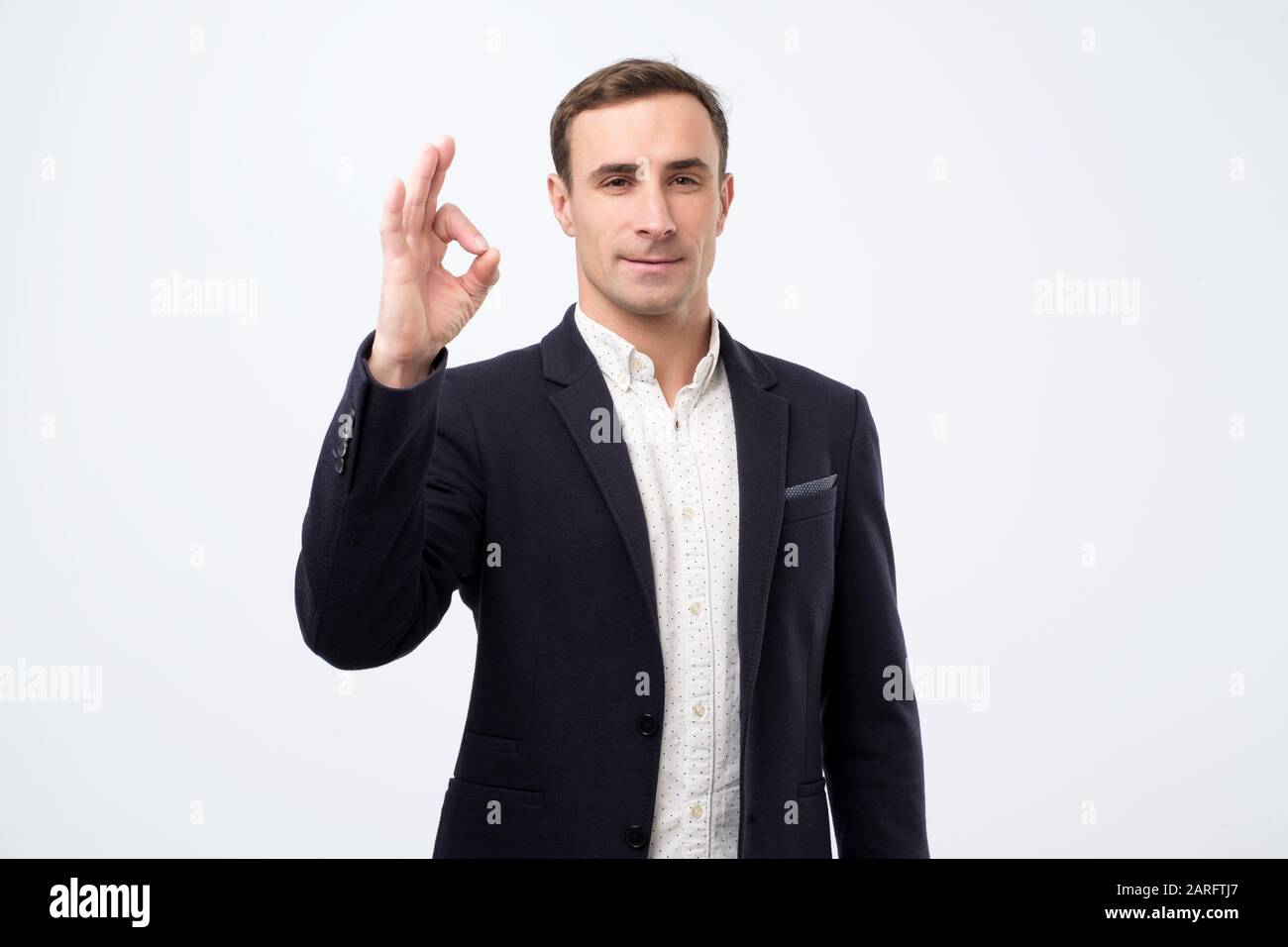 Portrait of cheerful italian young man in suit showing okay gesture ...