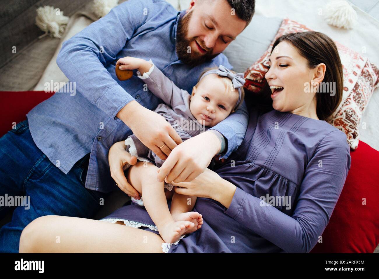 Family in blue clothes happily play with a child on the floor Stock ...