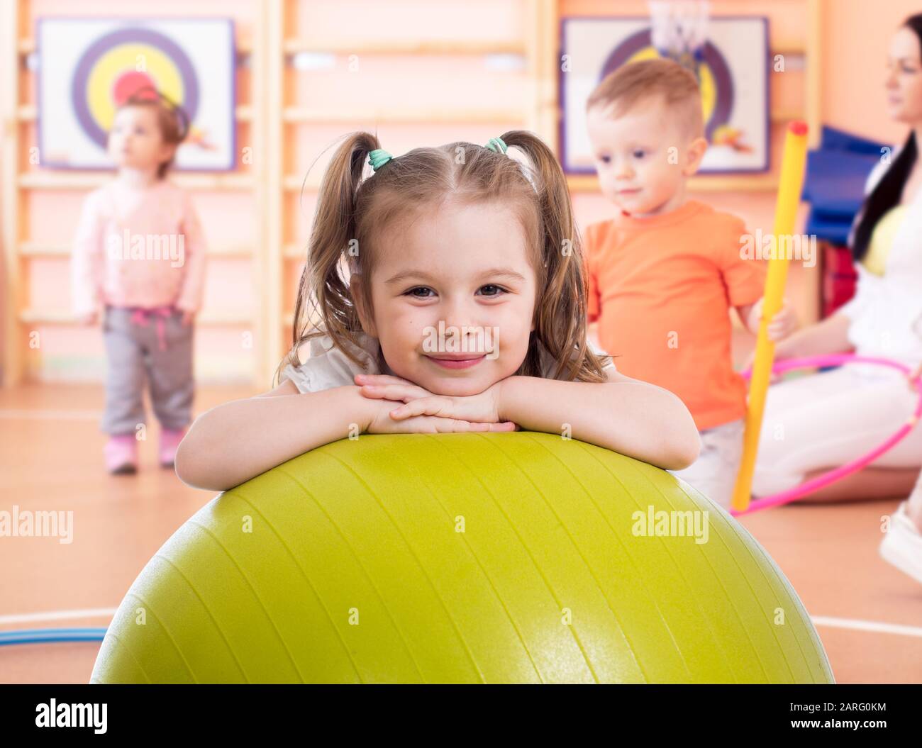 Smiling pretty child with fitness ball in gym. Gym class for preschool ...