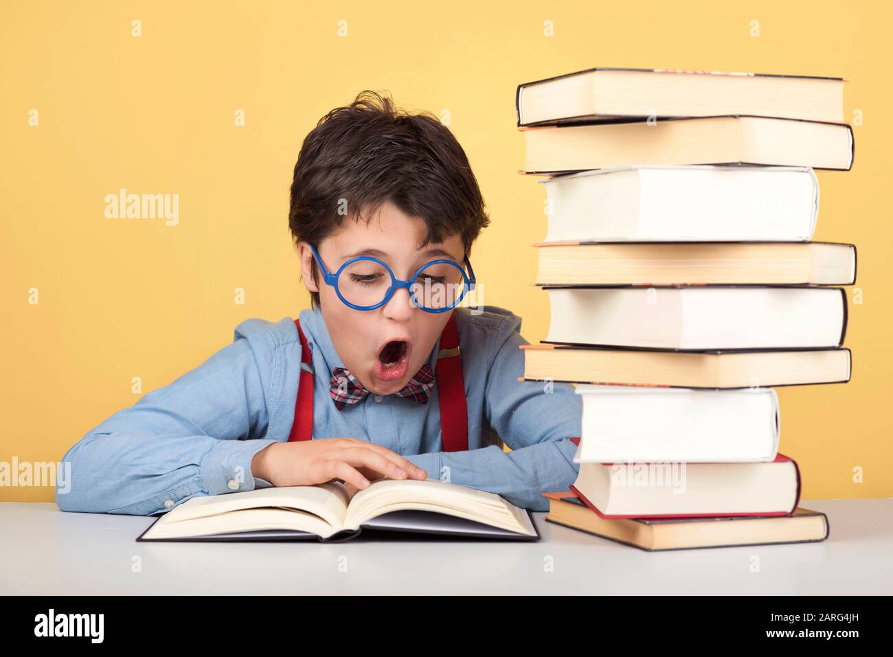 surprised boy reading a book on yellow background Stock Photo - Alamy