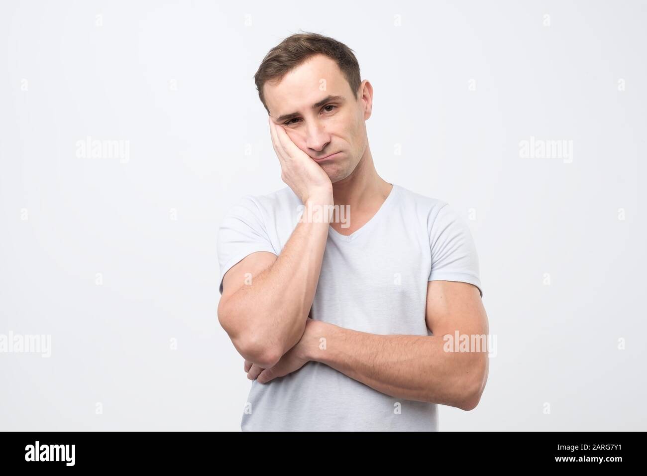 Very bored adult man holding hand on cheek looking tired and sick, over ...