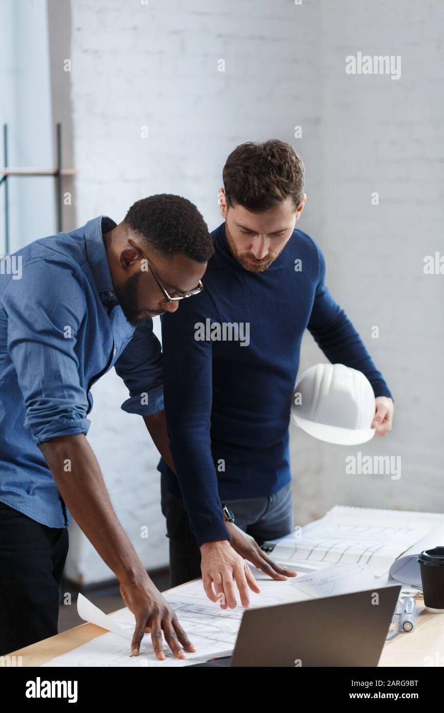 Multiracial engineer team working in office with blue prints and ...